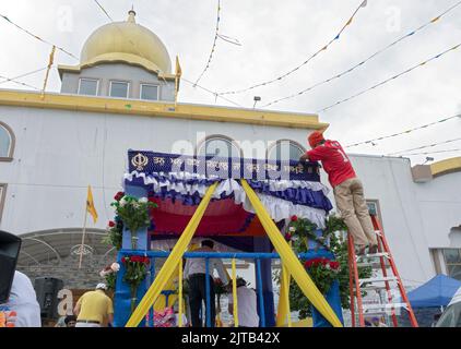 A Sikh man puts bunting on the mani float of the 2022 Nagar Kirtan ...