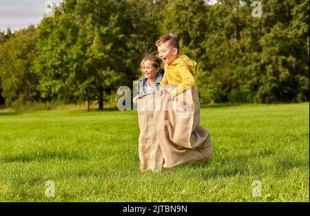 happy children playing bag jumping game at park Stock Photo - Alamy