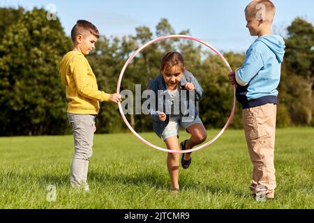 happy children playing game with hula hoop at park Stock Photo - Alamy
