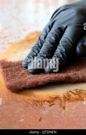 Rubbing rust off sheet steel with an abrasive pad. Restoration project ...