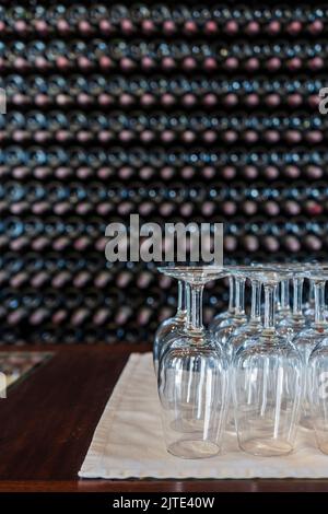 Empty wine glasses with many stacked bottles as a background ...