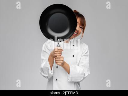 female chef peeking out from behind frying pan Stock Photo - Alamy