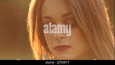 Pensive young woman during dreamlike golden hour sunset time ...