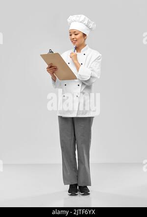 thinking female chef with clipboard and pen Stock Photo - Alamy