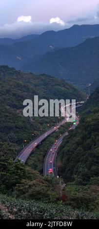 curved highway through the green rice fields with houses scattered ...
