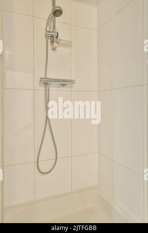 Shower faucets attached to tiled wall near glass partition and ...