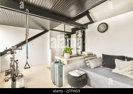 Comfortable chair placed near table with wardobe and shelves in light ...