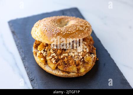 A closeup shot of an open cut bagel with delicious meat, vegetables ...