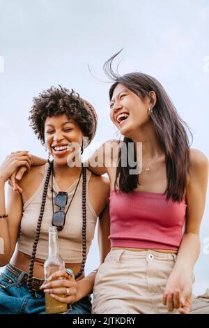 Two cheerful young women laughing and splashing in the clear blue water ...