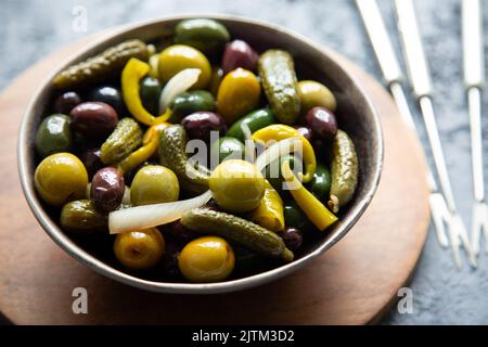 Pickled gherkins, onion, chilli and various types of olives in a bowl ...
