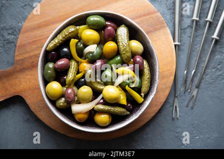 Pickled gherkins, onion, chilli and various types of olives in a bowl ...