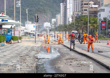 cleaning workers removing sand from the Leblon beach boardwalk in Rio ...