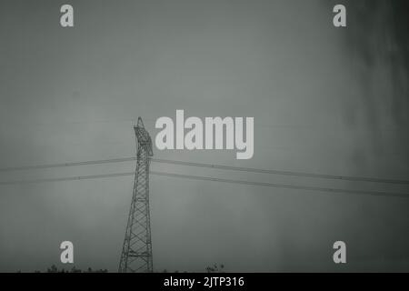 A grayscale shot of a metallic electricity pole with mist around Stock ...
