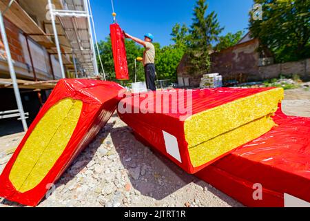 Worker on scaffold elevator insulating wall facade of new building ...