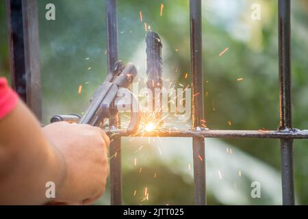 man using welding a piece of iron in an outdoor gate in Rio de Janeiro ...