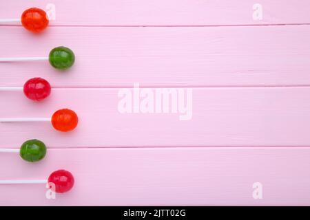 Red and green lollipops on pink wooden background. sweet candy concept ...