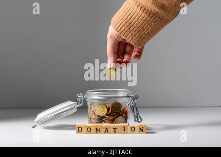 hand putting coin into jar and making donation Stock Photo - Alamy