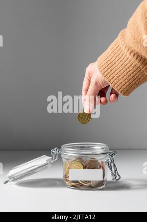 hand putting coin into jar and making donation Stock Photo - Alamy
