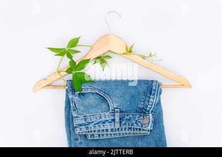 Upcycling clothes concept. Jeans on wooden hanger with green leaves ...