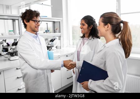 scientists shaking hands in laboratory Stock Photo - Alamy
