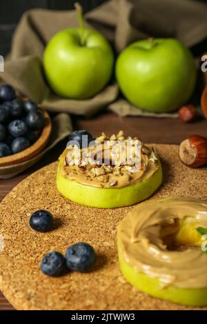 Cork mat of tasty apple rounds with nut butter on wooden table Stock ...