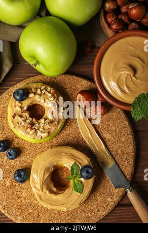 Cork mat of tasty apple rounds with nut butter on wooden table Stock ...
