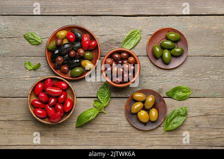 Bowls and plates with different kinds of delicious olives on wooden ...