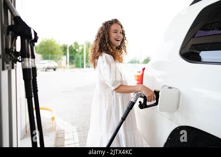 Young curly woman refueling car at gas station Stock Photo - Alamy