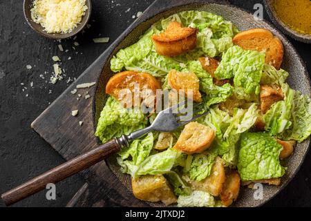Plate with tasty Caesar salad on color wooden background Stock Photo ...