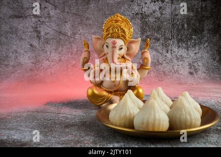 Idol of lord Ganesha with Modak Sweet Dish and flower. Ganesh chaturthi ...