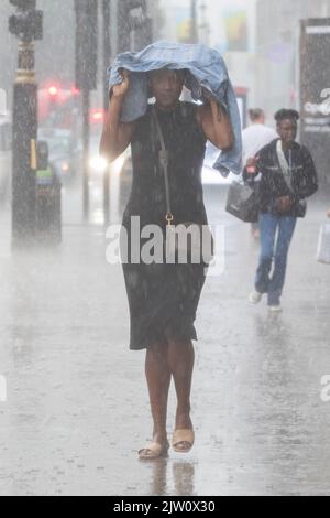 Amber rain catches Londoners this afternoon at Tower Bridge. Image shot ...