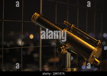 A vintage telescope in front of a window with a view of the starry sky ...