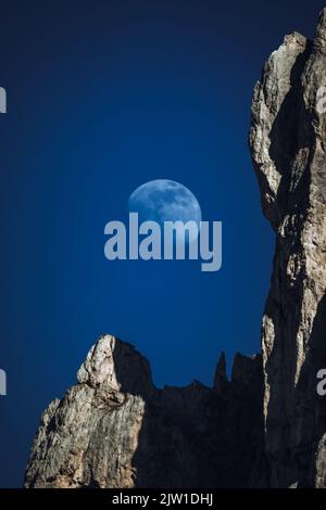 A rocky cliff with the fading moon in the background Stock Photo - Alamy