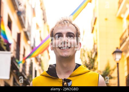 From below happy non binary male in stylish clothes smiling and looking ...