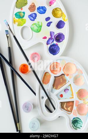 From above of watercolor paint palettes and abstract pictures arranged ...
