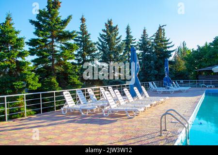 Primorsk, Ukraine. Poolside. Sunbeds near swimming pool surrounded by ...