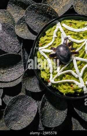 Spooky Halloween black potato chips with guacamole dip Stock Photo - Alamy