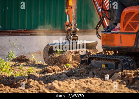 A minitractor rakes the earth with a bucket. Land works Stock Photo - Alamy