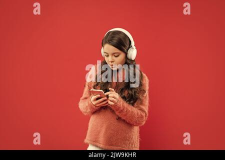 busy child in sweater listen music in headphones and messaging on ...