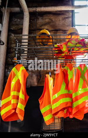 Orange safety vests hang on rack in old building Stock Photo - Alamy