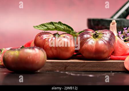 Tiger tomato on a cutting board with basil leaves on wooden background ...