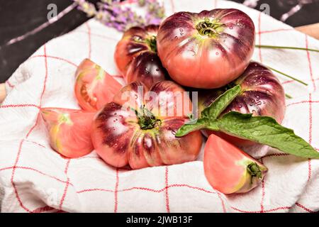 Tiger tomato on a cutting board with basil leaves on wooden background ...