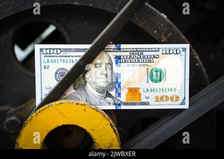 Hundred dollar bill in a tractor pulley close-up with a blurred ...