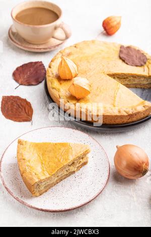 Autumn onion pie decorated with leaves and cup of coffee on white ...