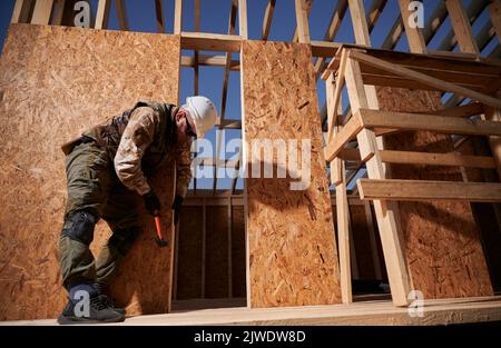 Carpenter hammering nail into OSB panel on the roof top of future ...