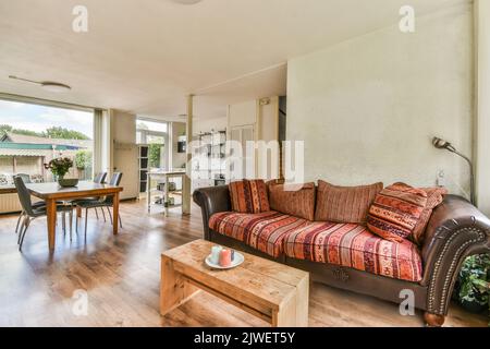 Shabby wooden table with chairs and vase located near comfortable couch ...