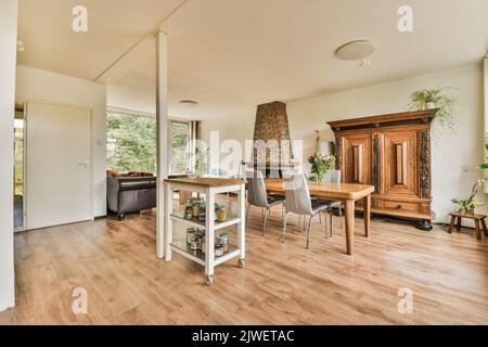 Shabby wooden table with chairs and vase located near comfortable couch ...