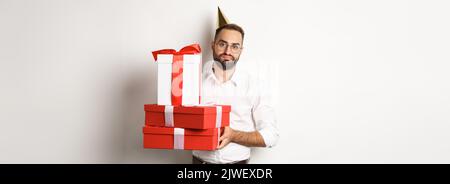 Holidays and celebration. Displeased guy holding birthday gifts and ...