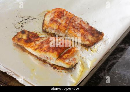Two baked barramundi fish fillet slices with paprika spice rub on blue ...