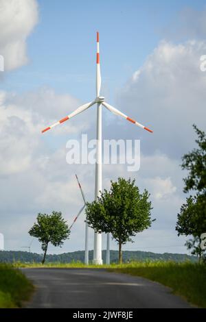 A vertical shot of tall wind turbine in the field on blue sky ...
